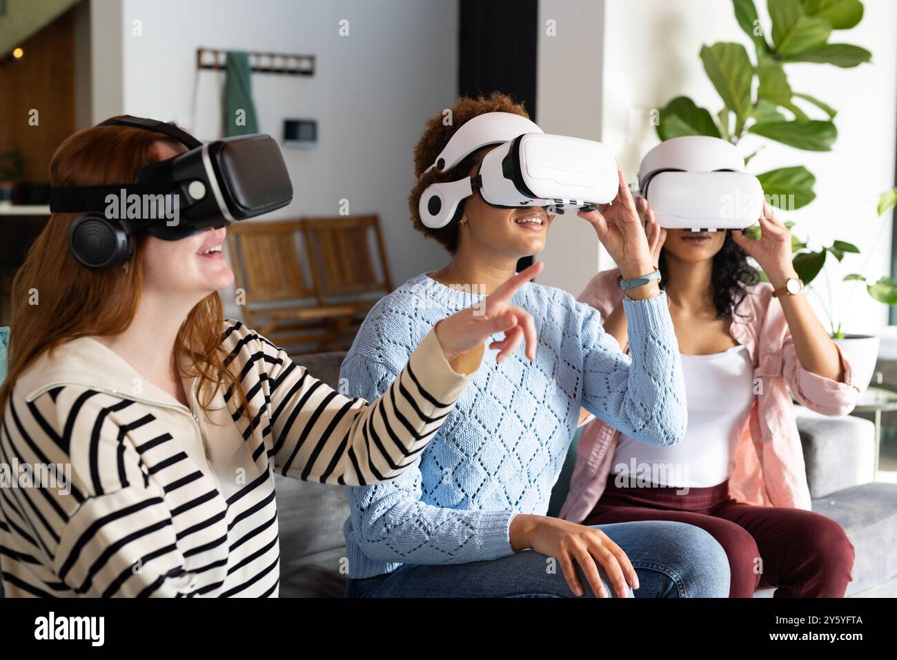 Using VR headsets, diverse women friends enjoying virtual reality ...