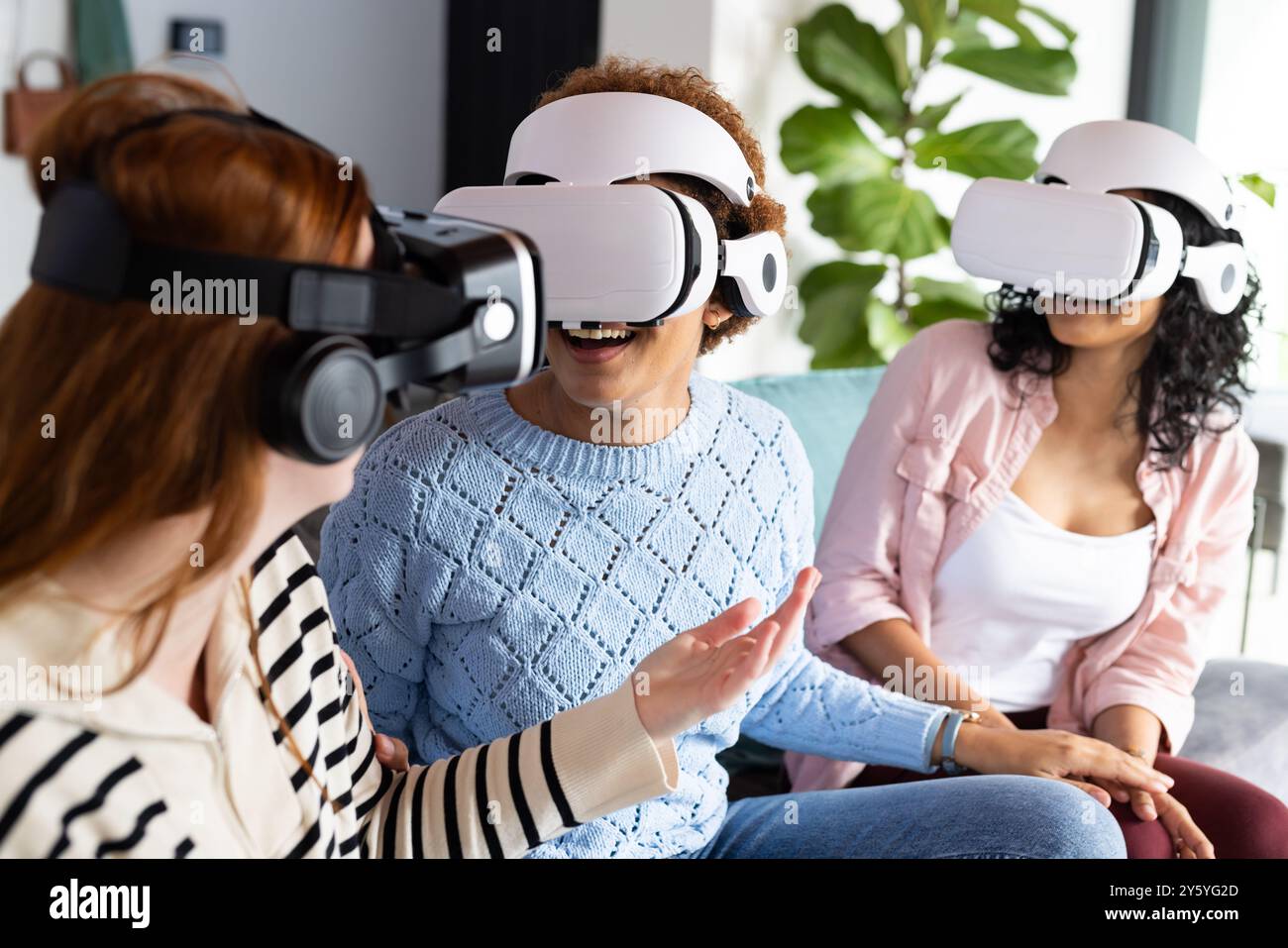 Using VR headsets, diverse women friends laughing and enjoying virtual ...