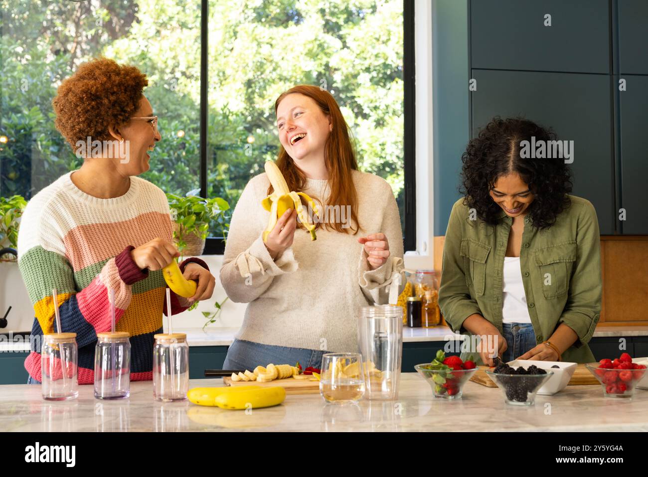 Preparing smoothies, diverse friends laughing and enjoying time ...