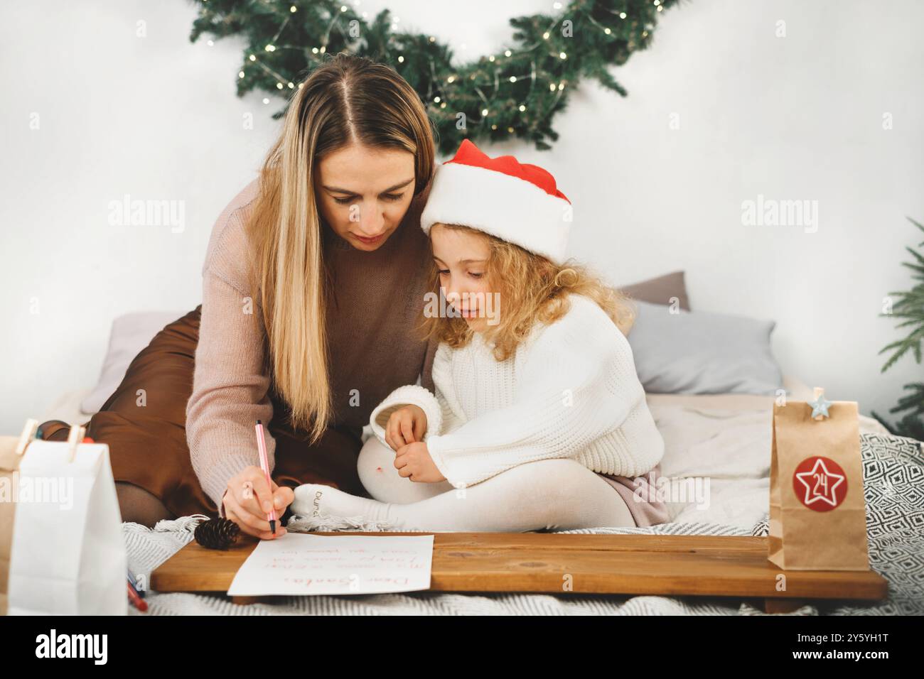 Mother with toddler girl writing Christmas letter and doing advent ...