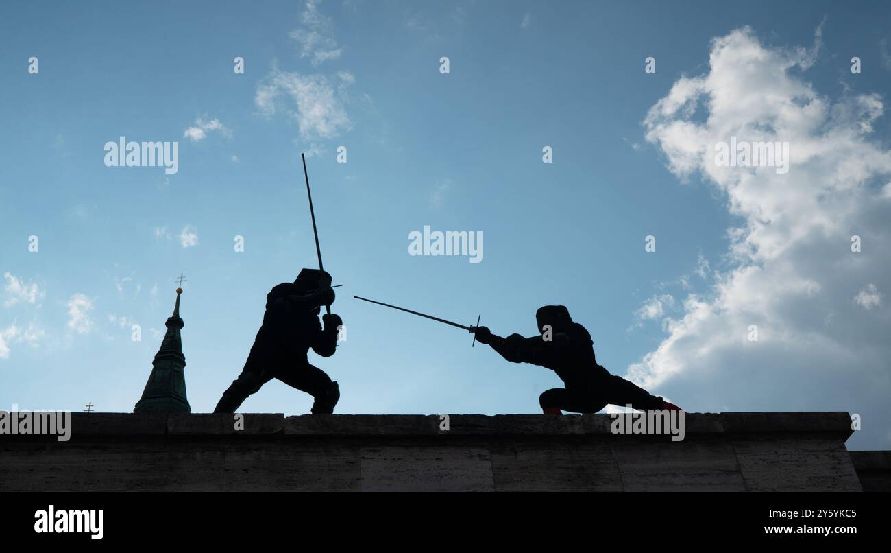 Two fencers dressed in black protective uniforms, helmets with face ...