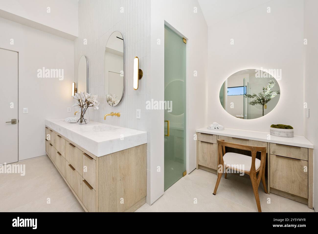Modern bathroom with light wood cabinets, large mirrors, and elegant ...
