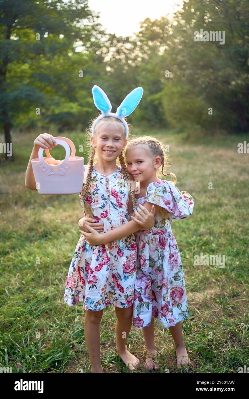 two little girls hug and play bunnies on an Easter egg hunt Stock Photo ...