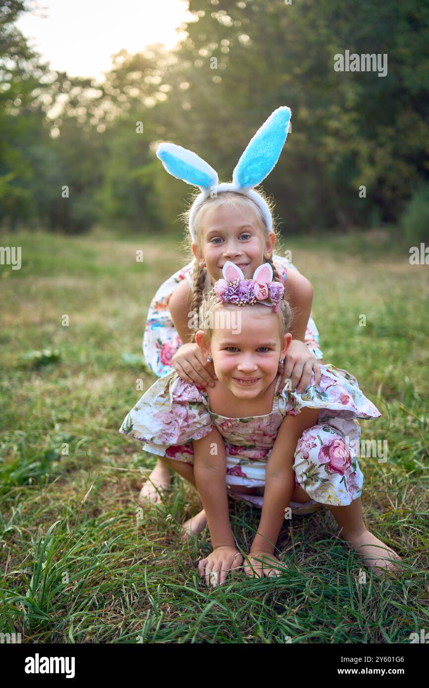 two little girls hug and play bunnies on an Easter egg hunt Stock Photo ...