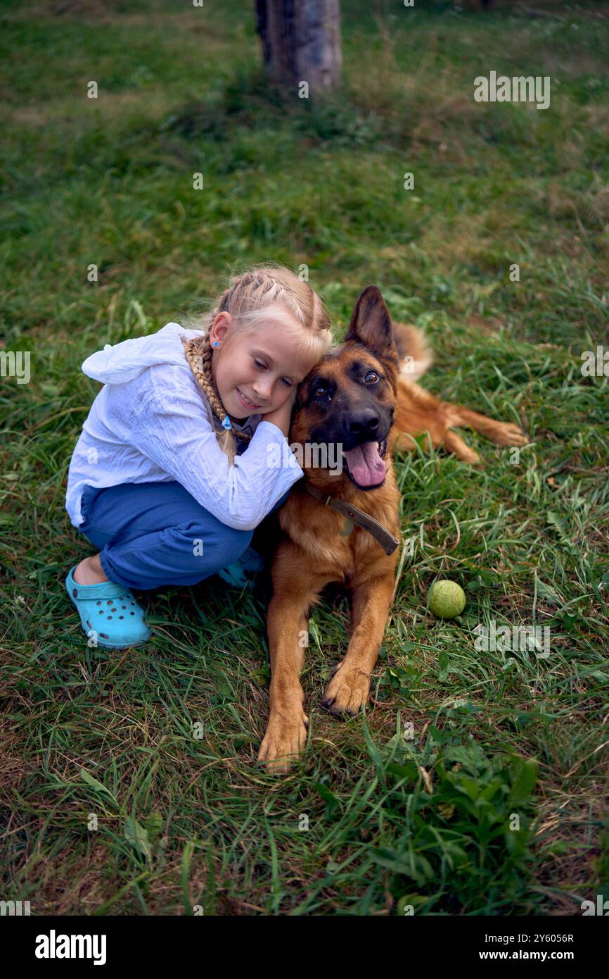 blonde girl of 8 years old hugs a German shepherd dog Stock Photo - Alamy