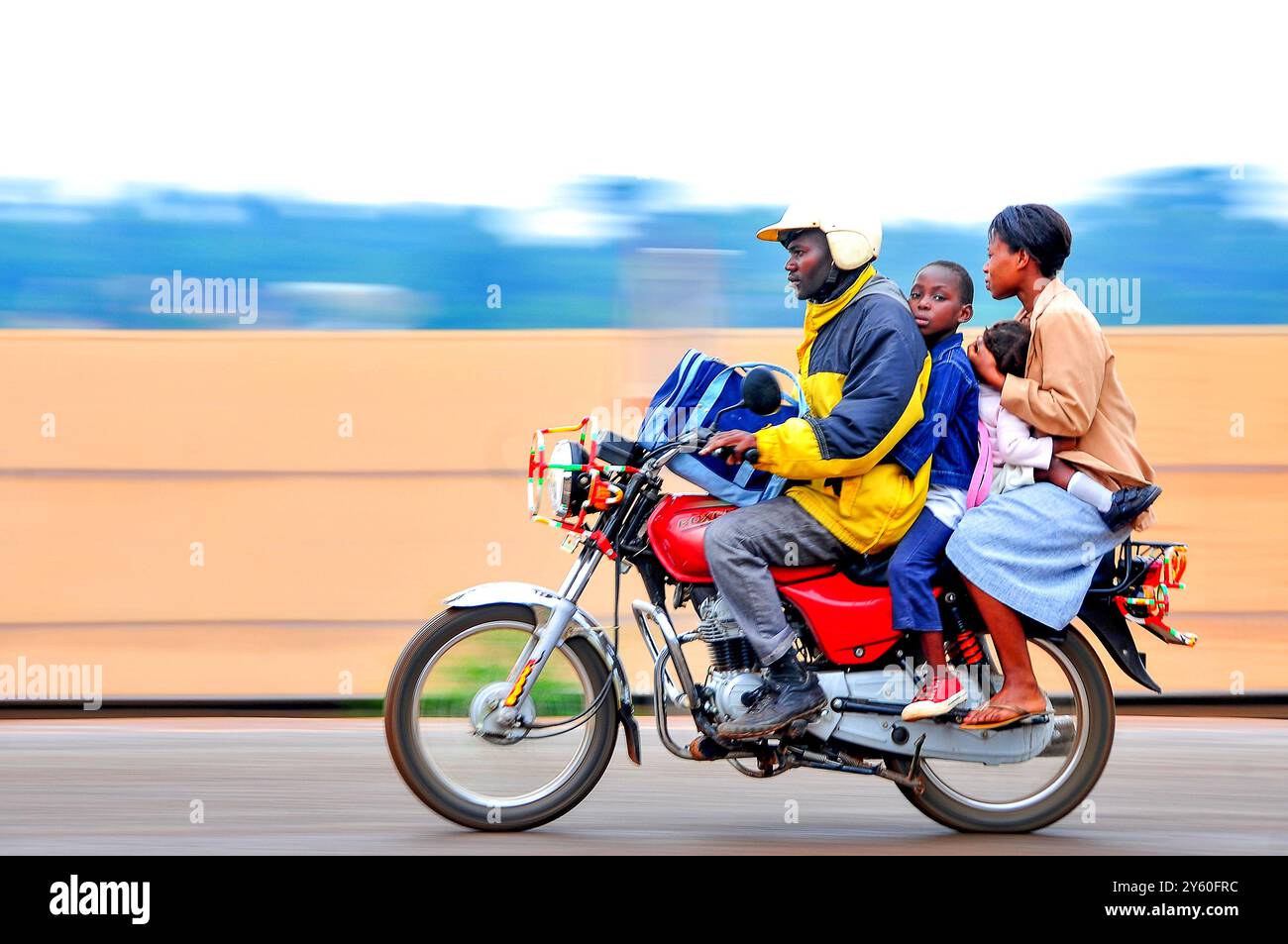 A motorcycle taxi known as boda boda carrying passengers in Kampala ...