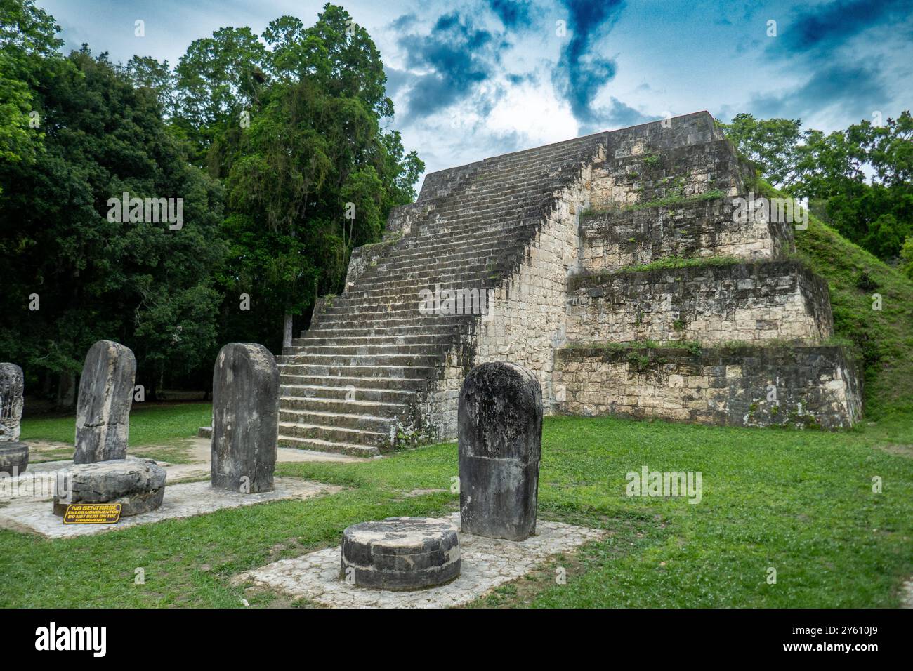 Ancient Mayan pyramid surrounded by lush greenery and stone monuments ...