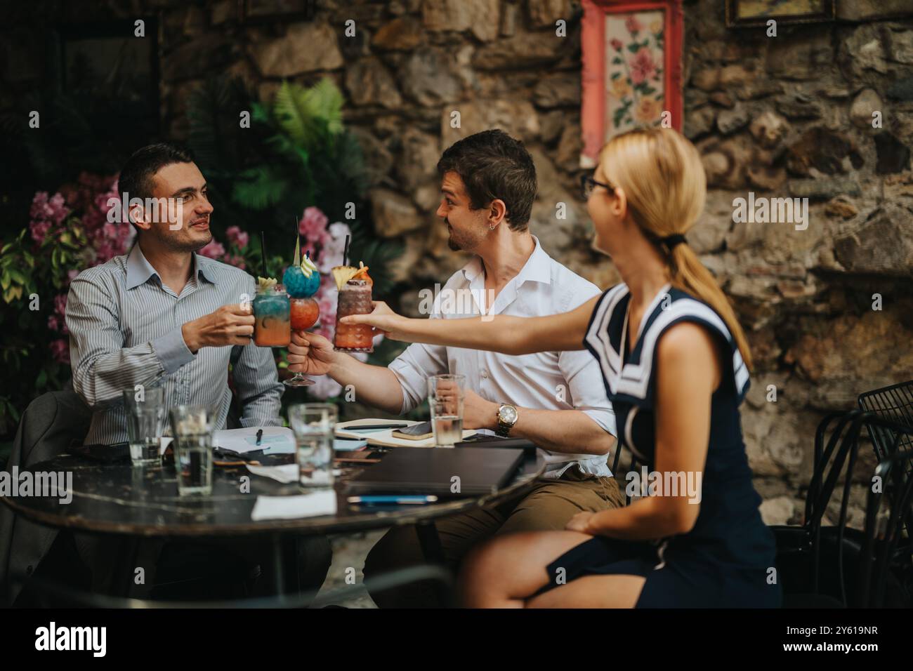 Friends enjoying cocktails at a lively outdoor cafe gathering Stock ...