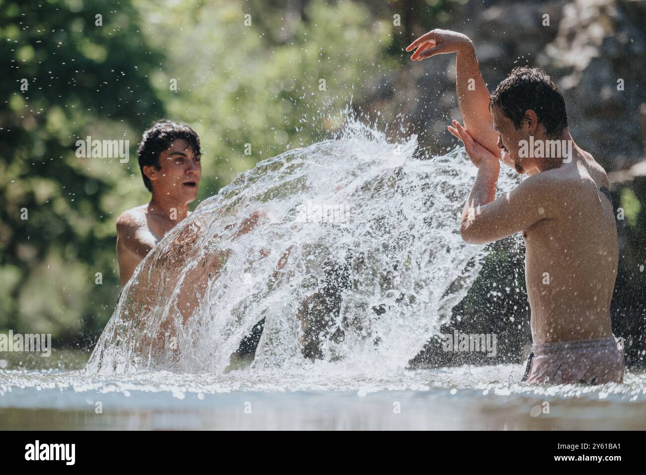 Two young friends splashing water in a sunny outdoor pond Stock Photo ...