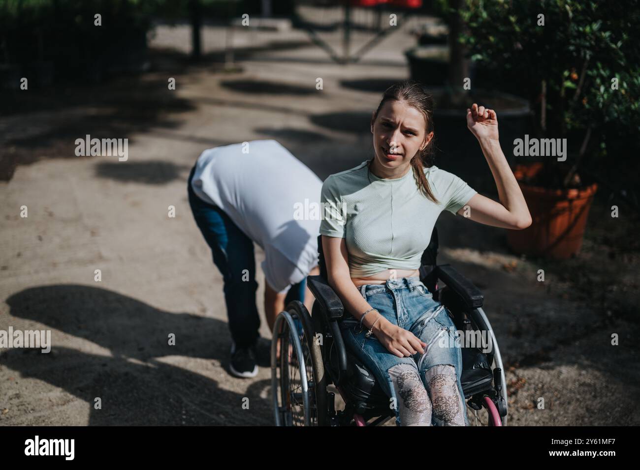 Young woman in wheelchair raising her hand outdoors Stock Photo - Alamy