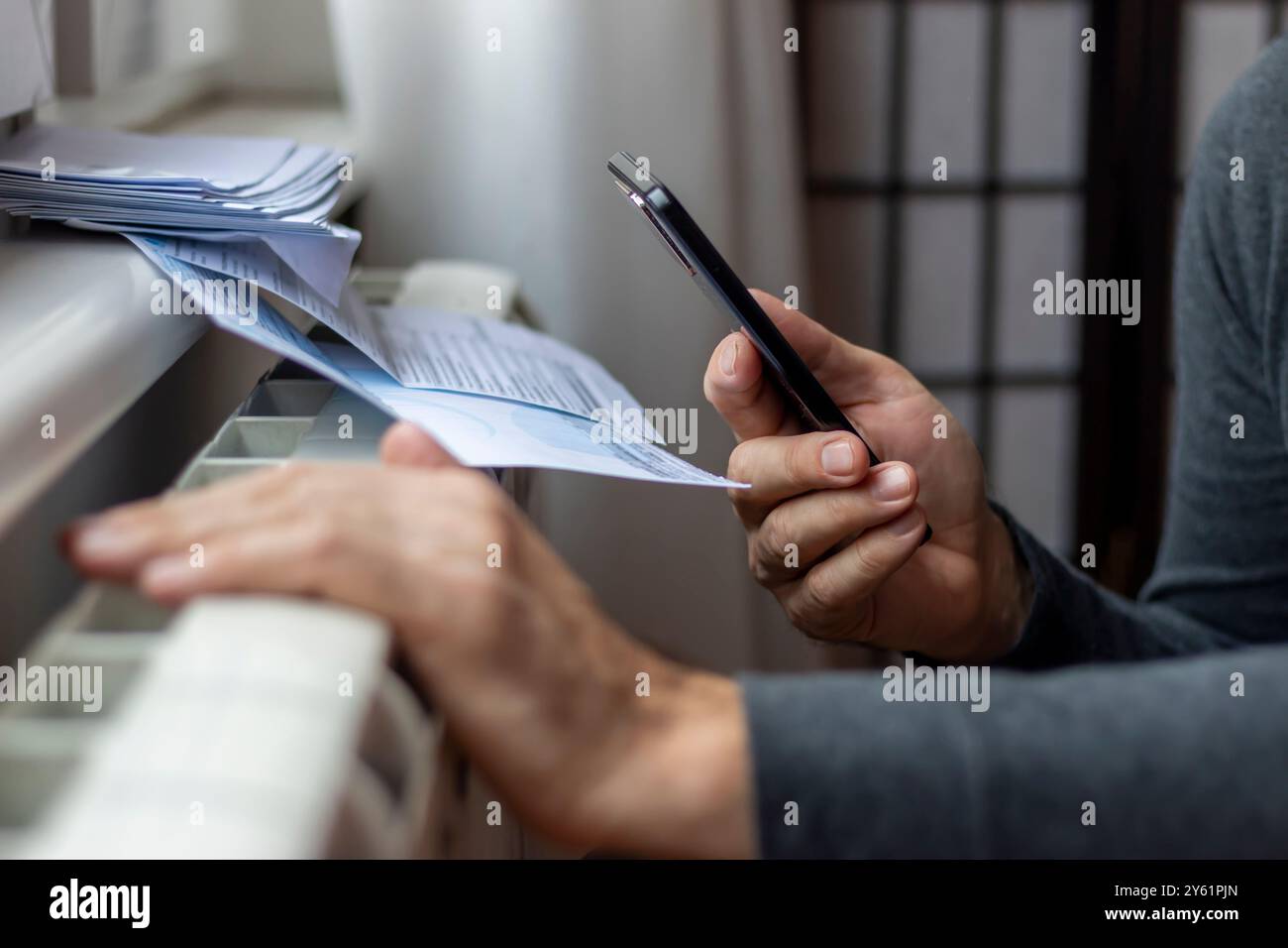Freezing man holding phone and check bills for electricity, gas and ...