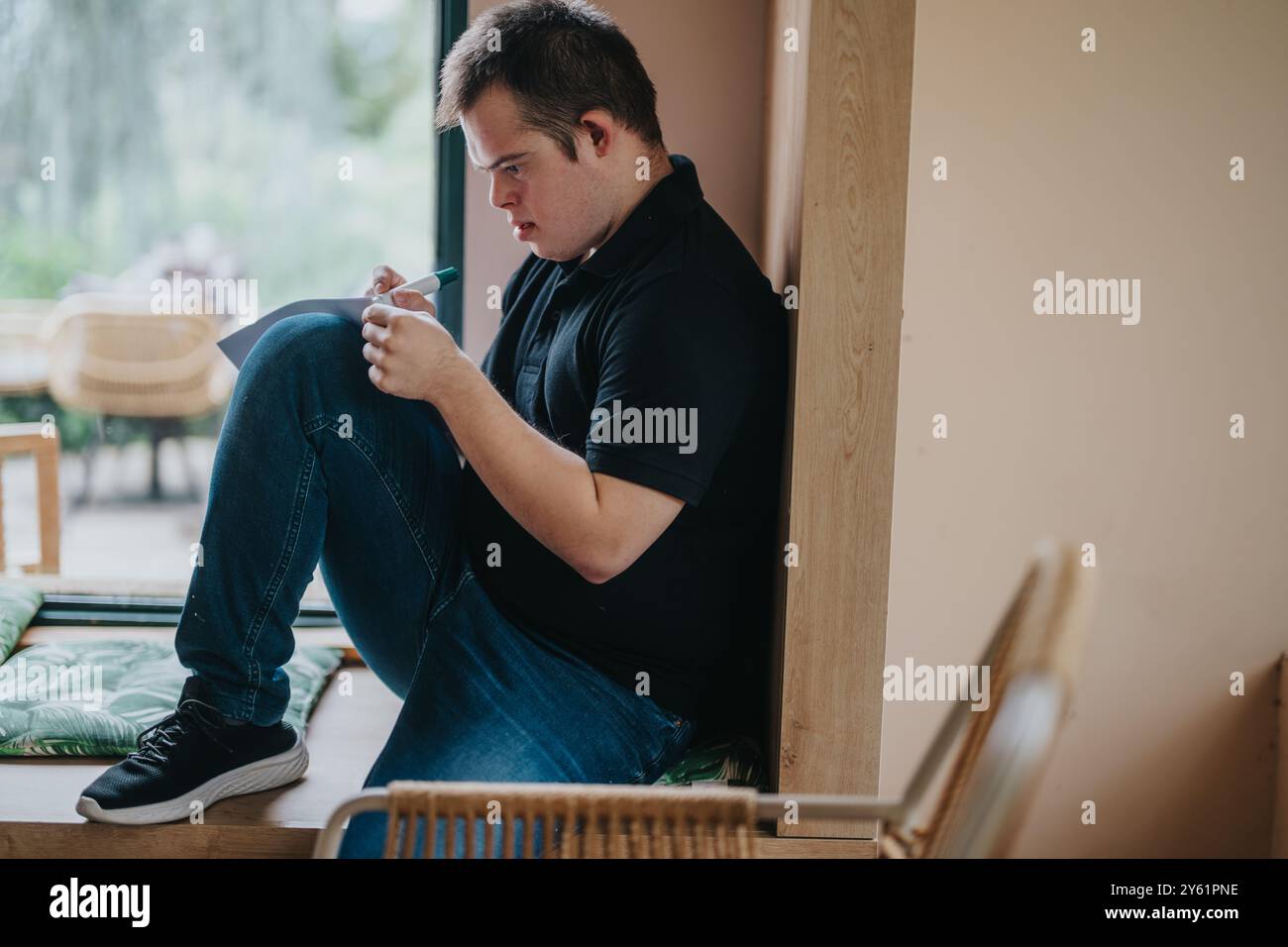 Young man with Down Syndrome writing in a cozy setting Stock Photo - Alamy