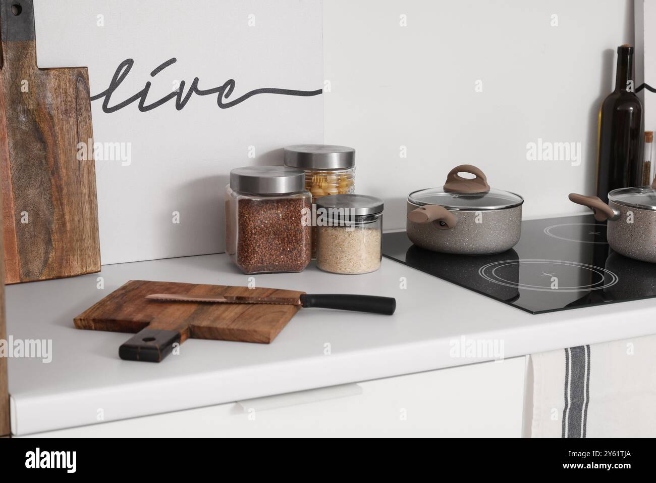 White kitchen counter with electric stove, cooking pots and utensils ...