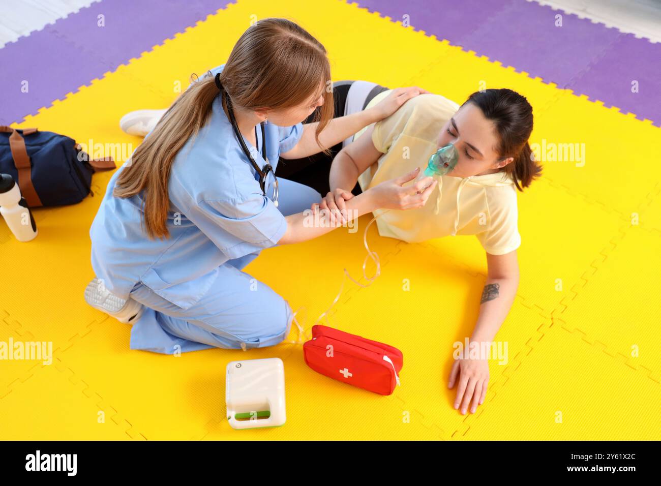 Female doctor with nebulizer giving young woman first aid in gym Stock ...