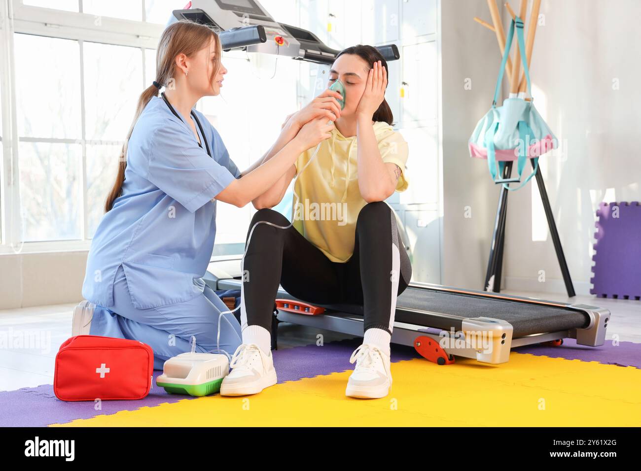 Female doctor with nebulizer giving young woman first aid in gym Stock ...