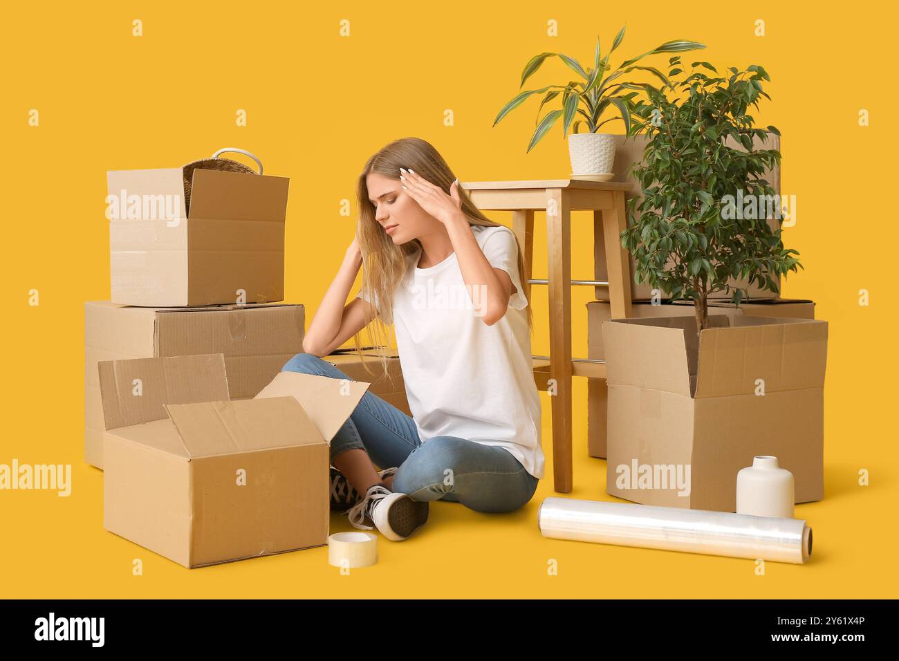 Stressed young woman packing her belongings in cardboard boxes on ...