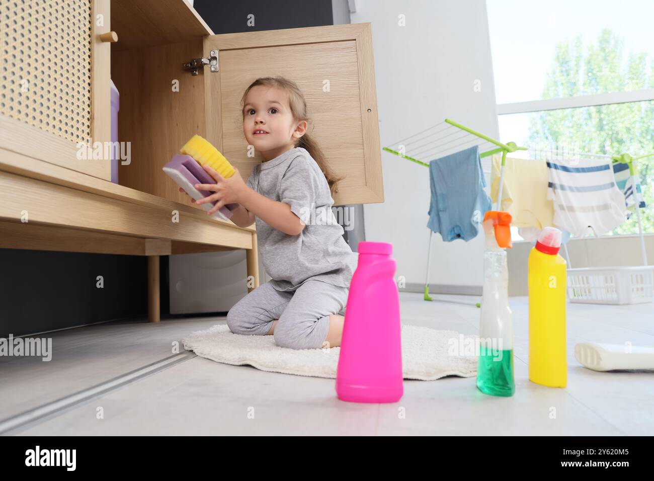 Cute little girl in laundry room. Child at risk Stock Photo - Alamy