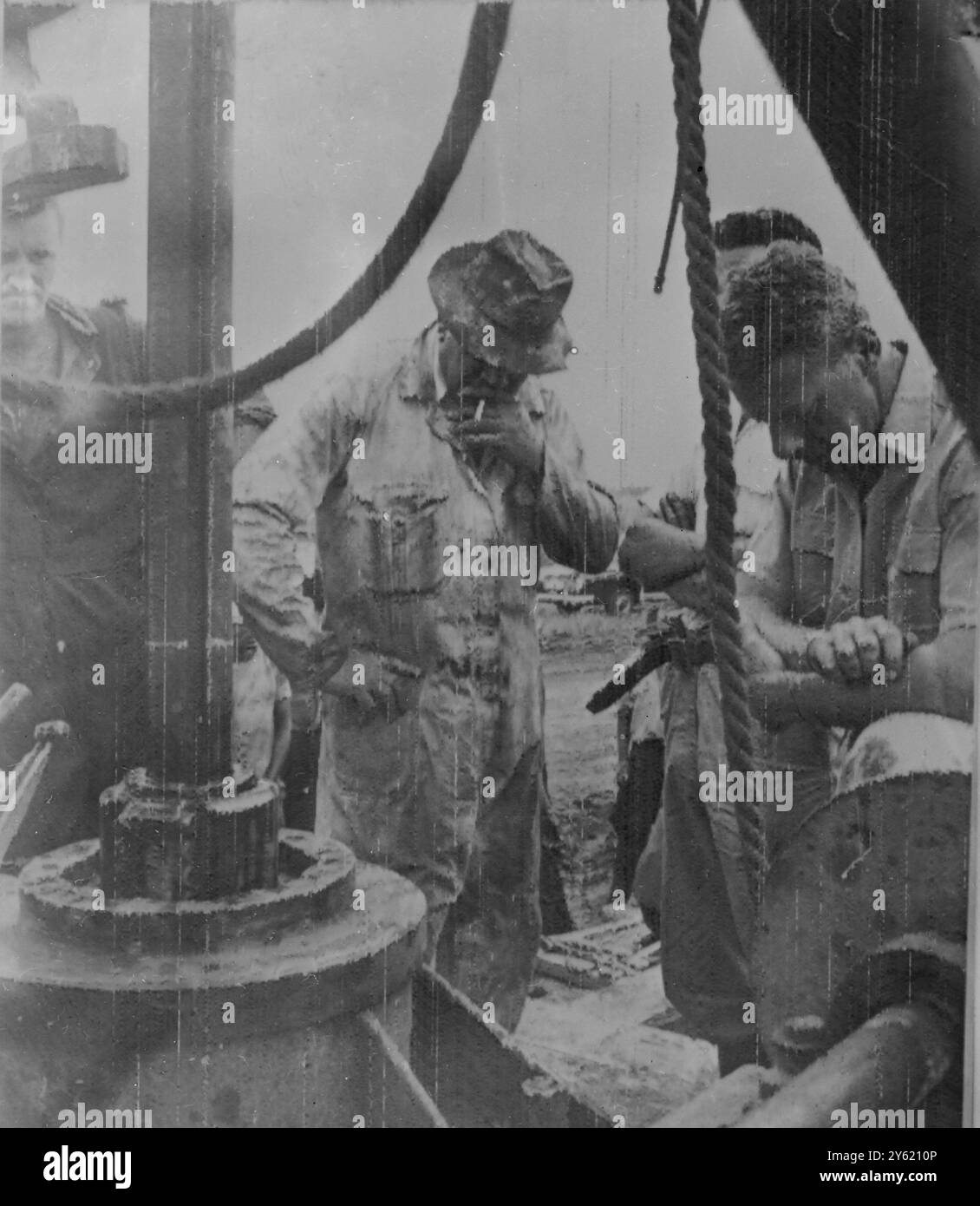 MINERS WATCH TENSELY AS DRILL BEGINS THE TASK OF DRILLING A BOREHOLE ...