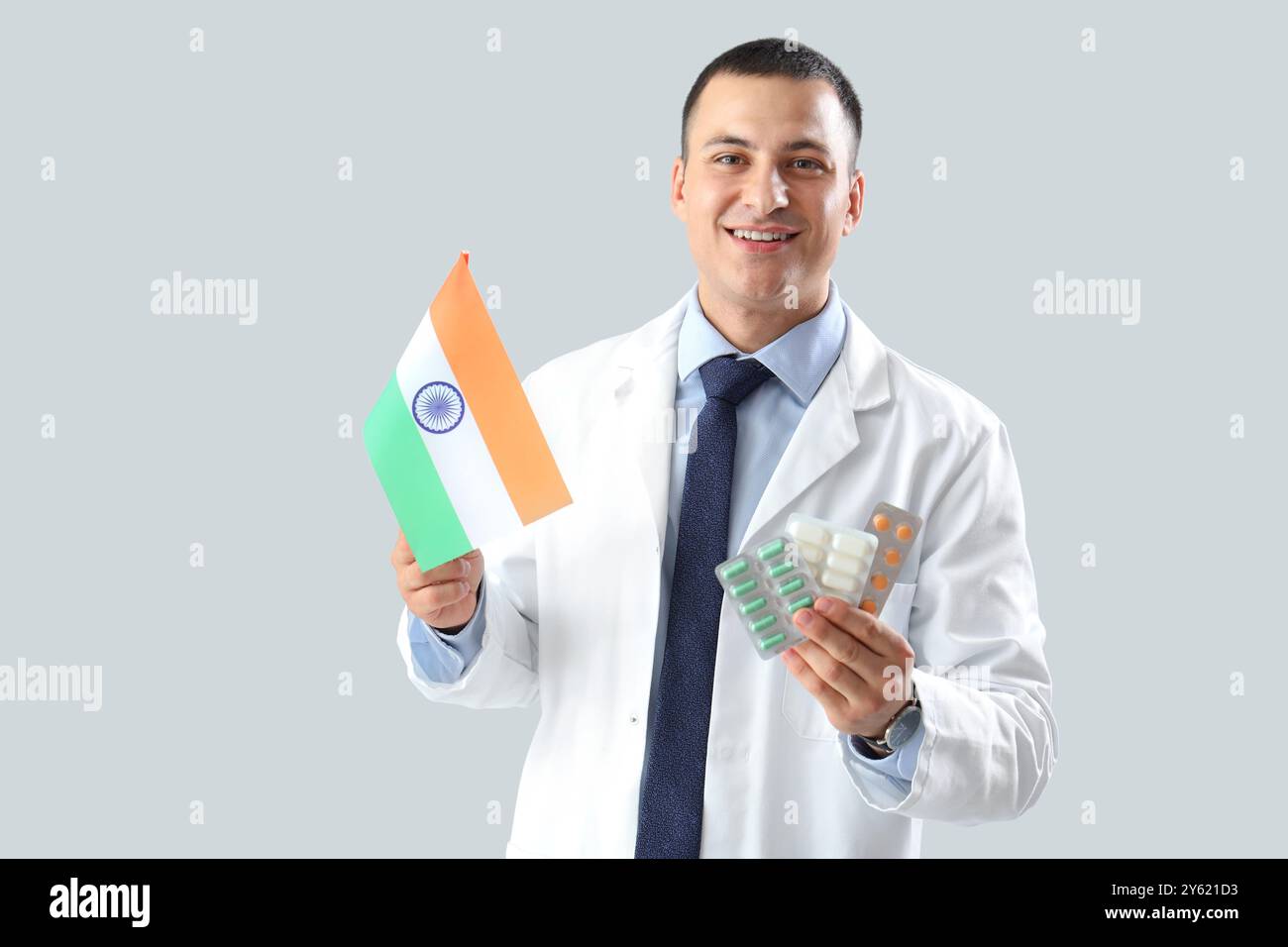 Male doctor with flag of India and pills on grey background. National ...