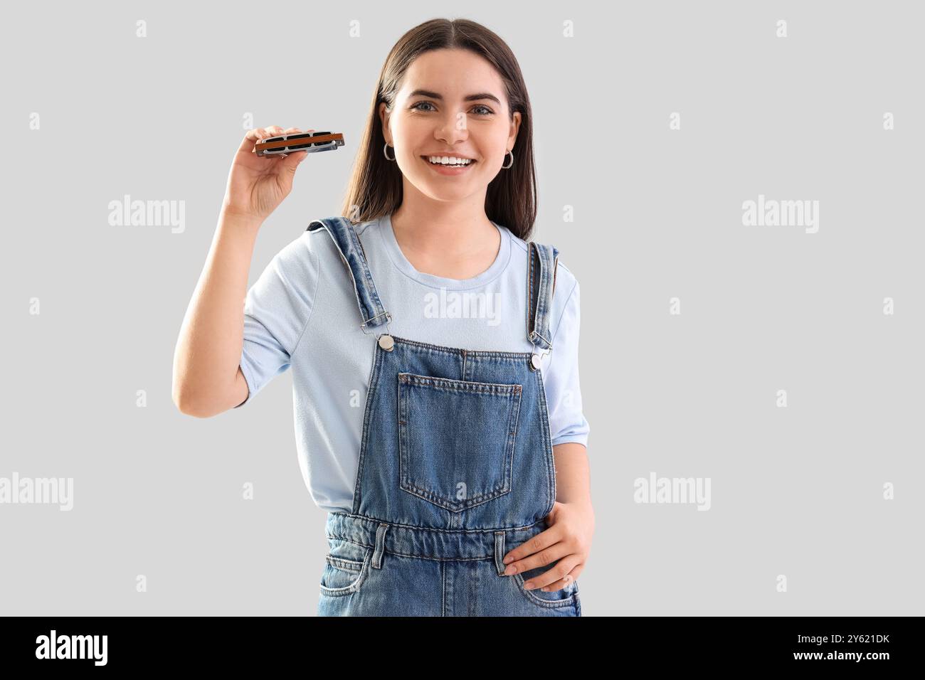 Young woman with harmonica on light background Stock Photo - Alamy