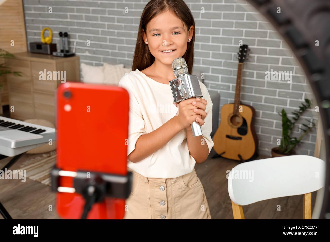 Singing little girl with microphone recording video at home Stock Photo ...