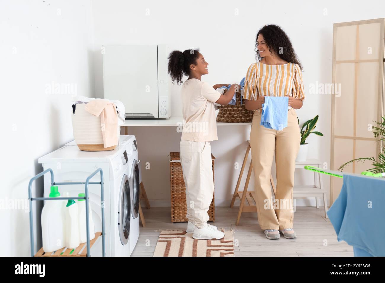 African-American woman and her daughter doing laundry at home Stock ...