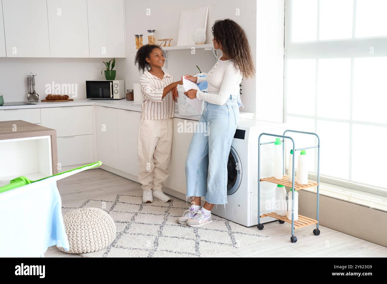 African-American woman and her daughter doing laundry at home Stock ...
