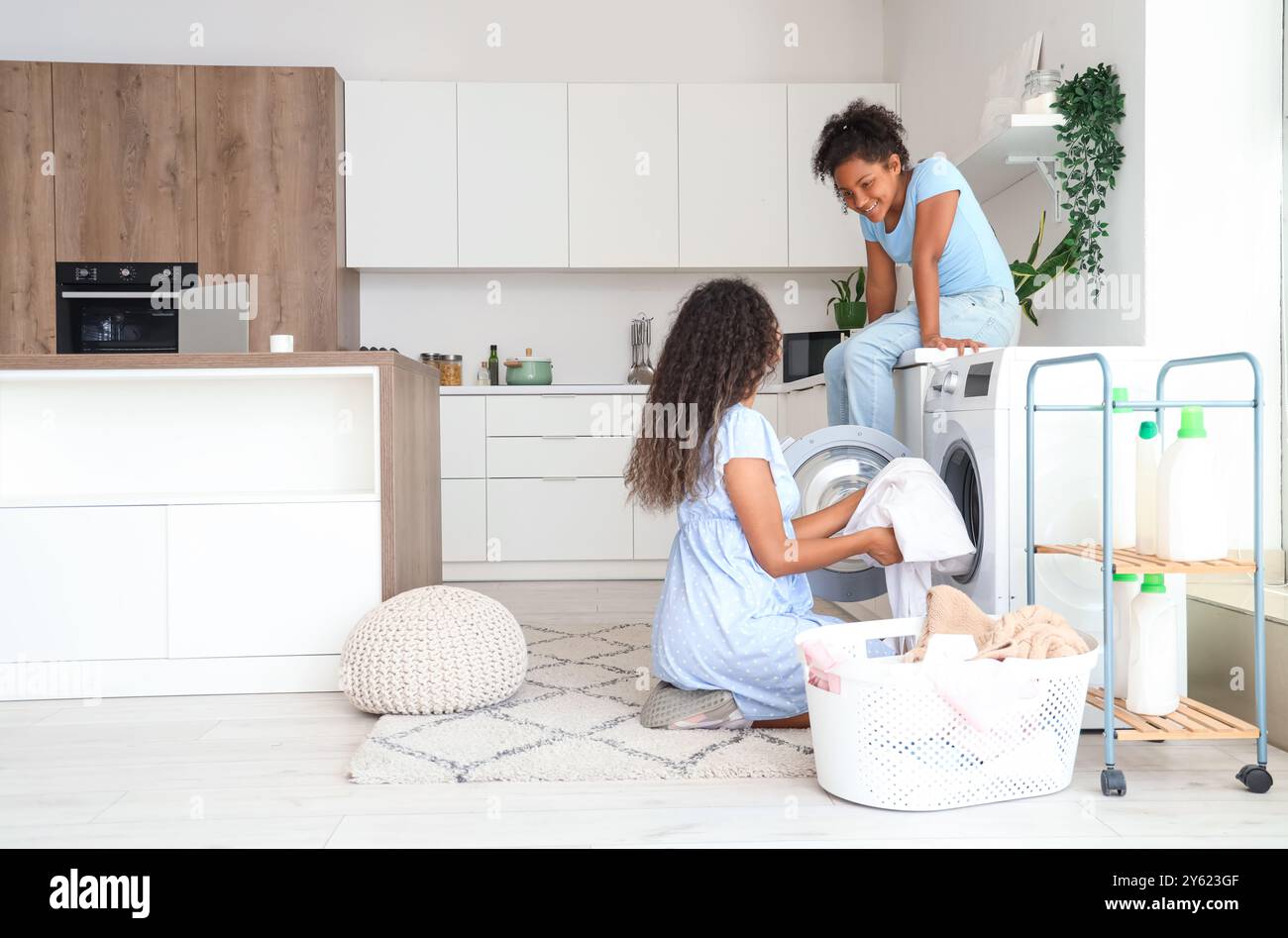 African-American woman and her daughter doing laundry at home Stock ...