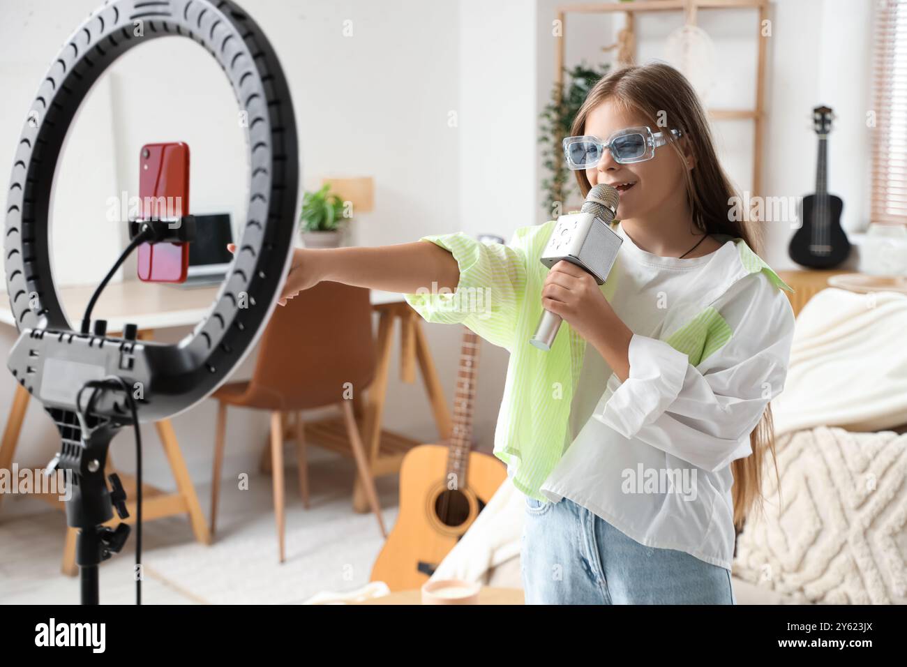 Singing little girl with microphone recording video at home Stock Photo ...