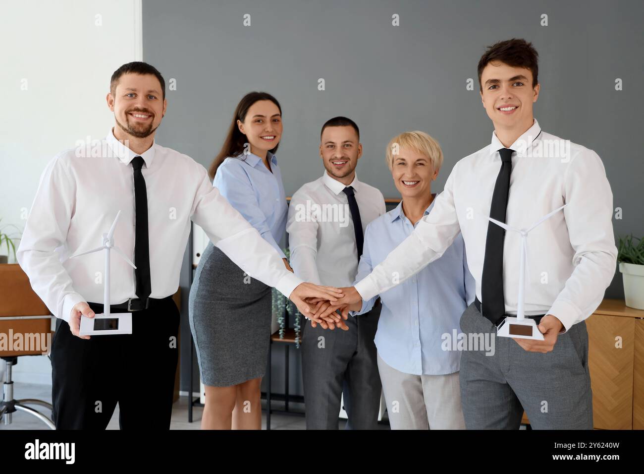 Group of engineers with wind turbine models putting hands together in ...