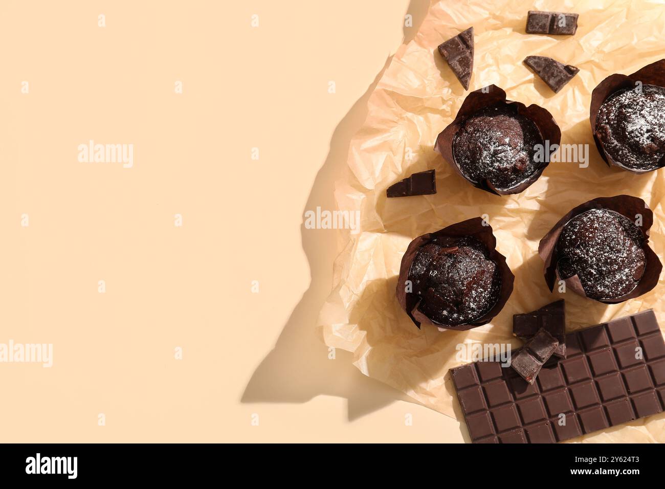 Baking paper with sweet chocolate muffins on beige background Stock ...