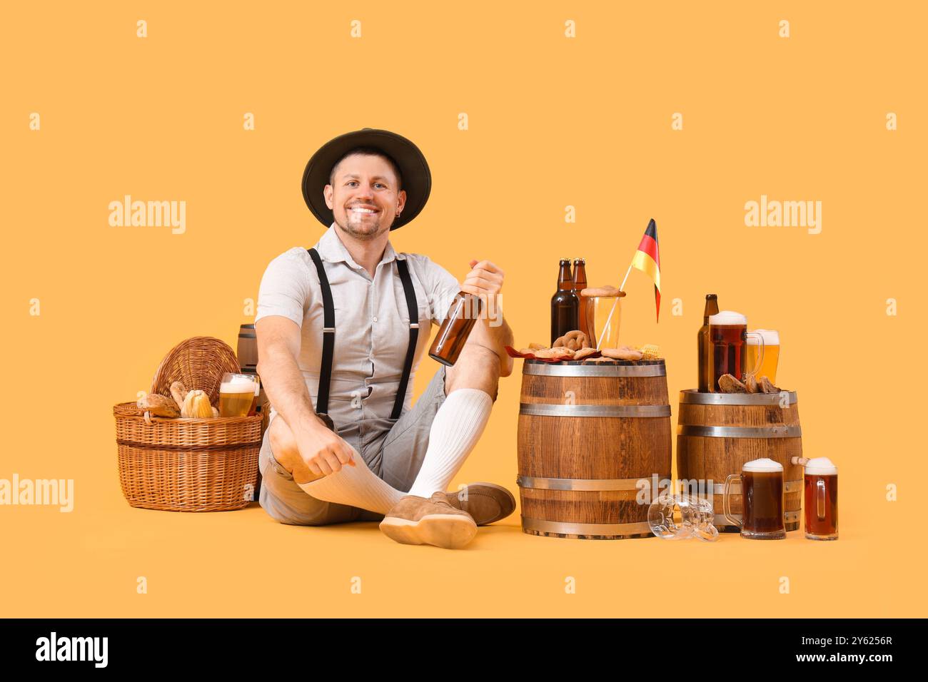 Mature happy man in traditional clothes with barrels, bottles of beer ...