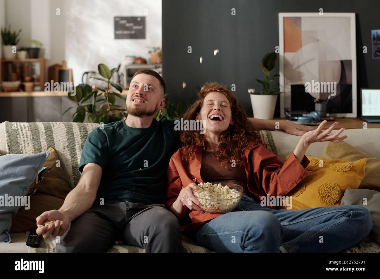 Young laughing woman and her boyfriend throwing up popcorn while ...