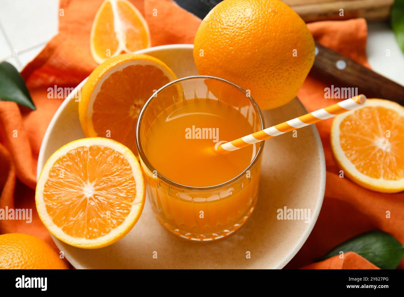 Glass of fresh orange juice and plate with fruits on white tile ...