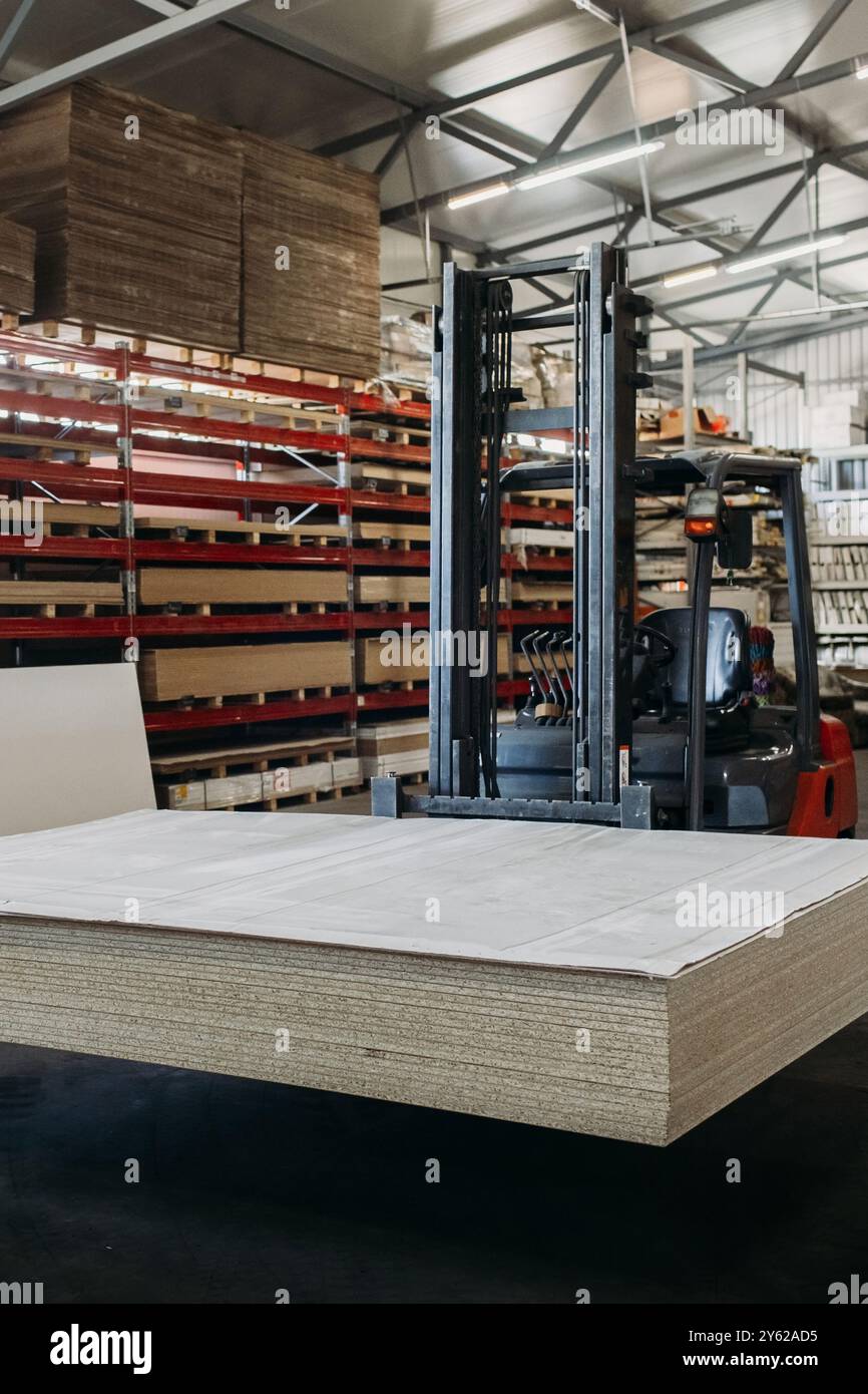 A forklift skillfully lifts a massive stack of sheets in a large, well ...
