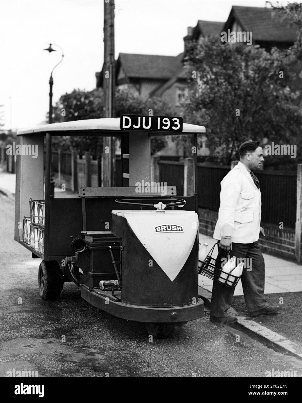 Milkman delivering milk in crate from float to house Stock Photo - Alamy