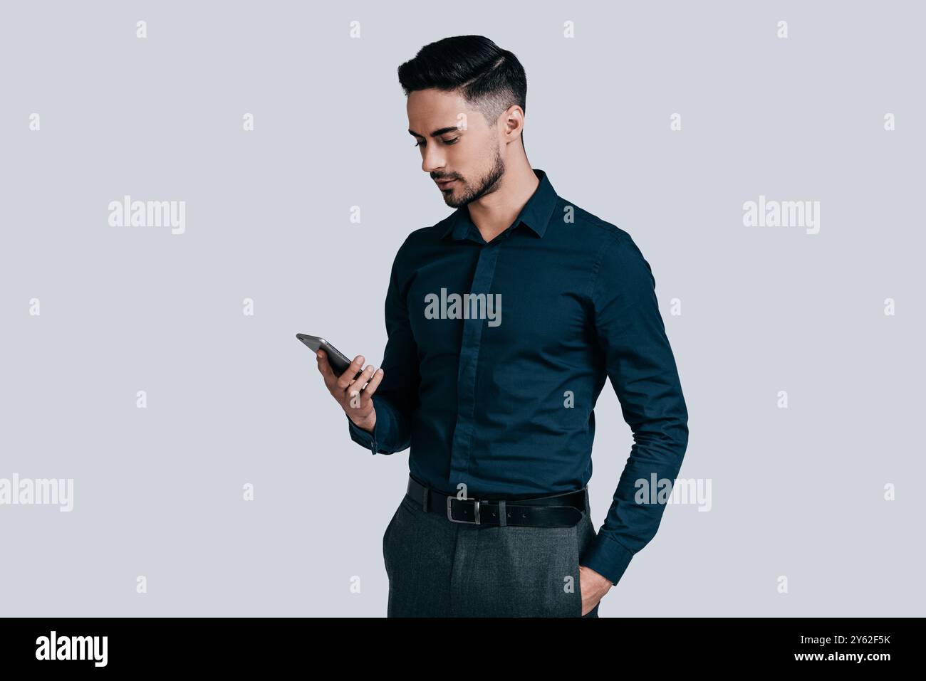 Sending important business messages. Serious young man in shirt typing ...