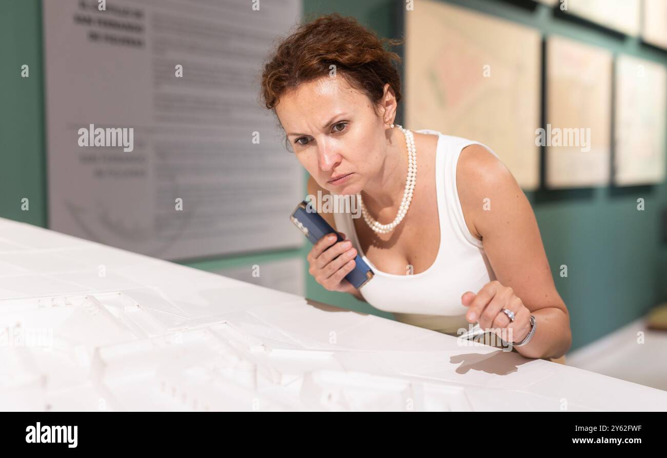 Middle-aged woman looking at building models in museum Stock Photo - Alamy
