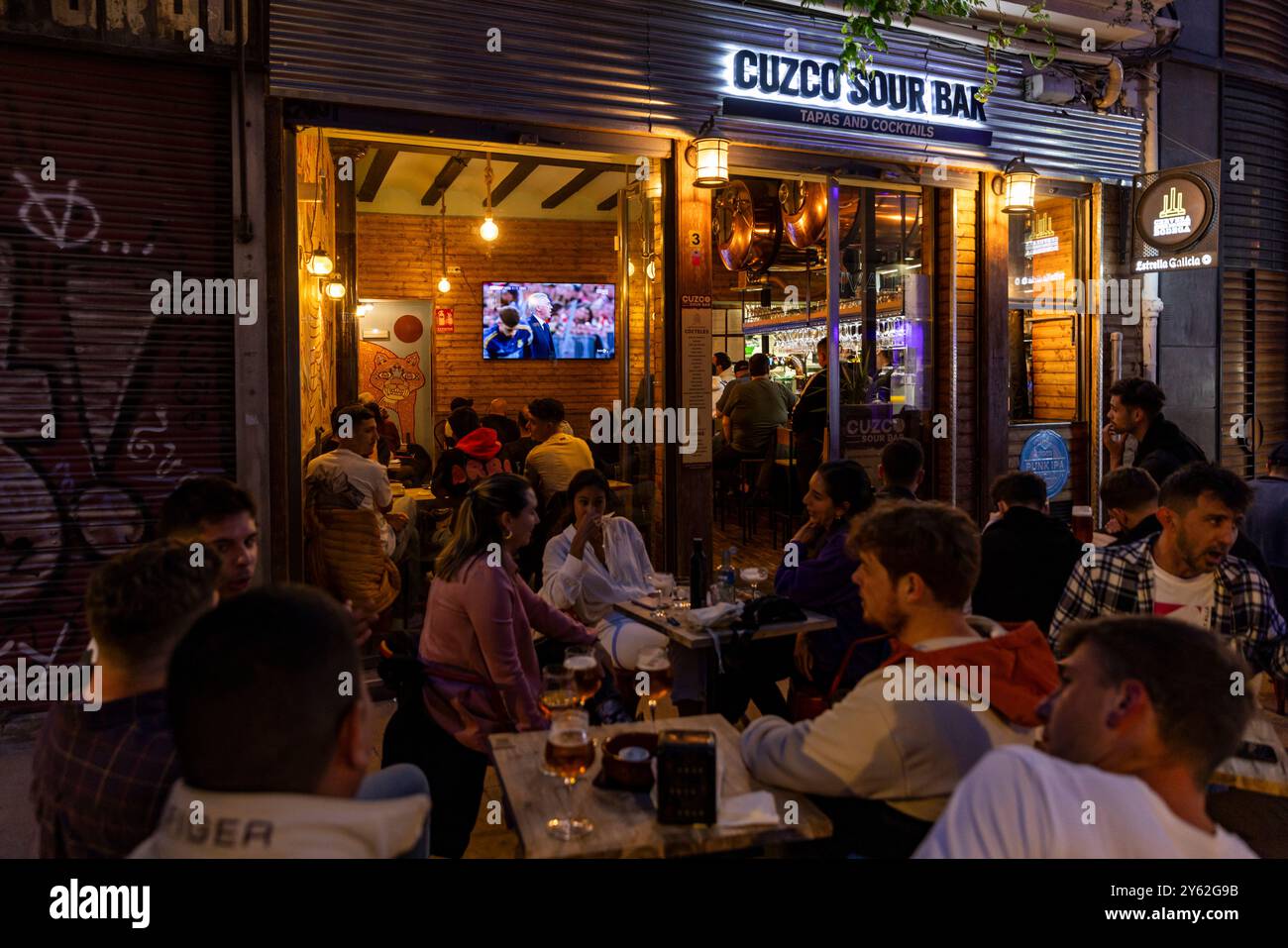 A busy street scene at night in Valencia, Spain with futbol on ...