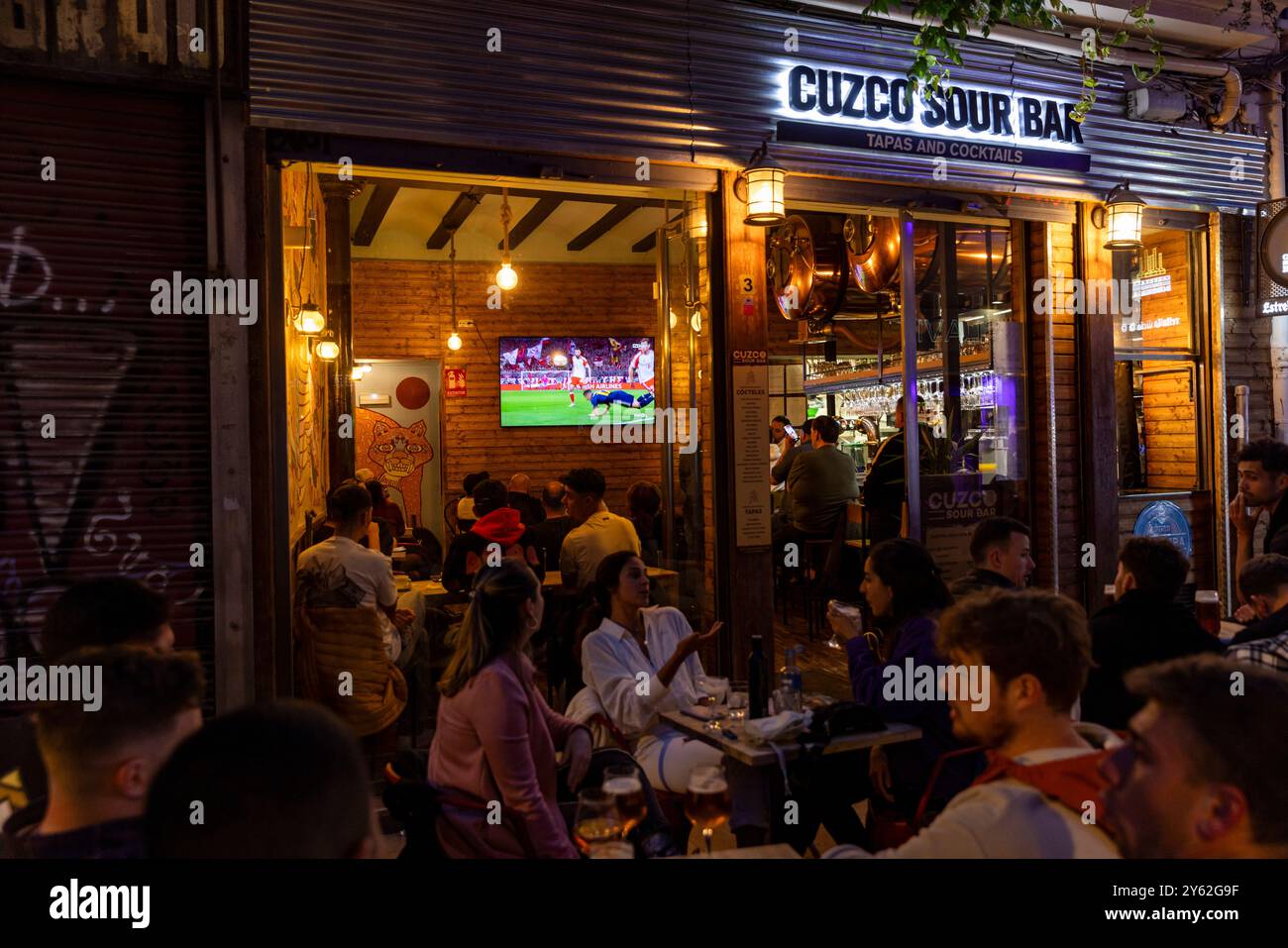 A busy street scene at night in Valencia, Spain with futbol on ...