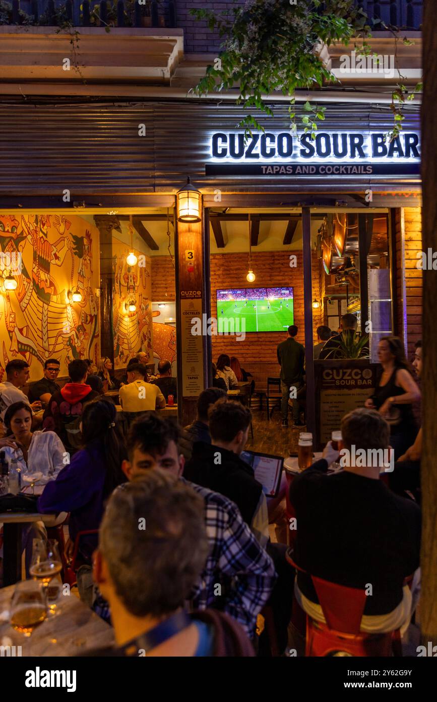 A busy street scene at night in Valencia, Spain with futbol on ...