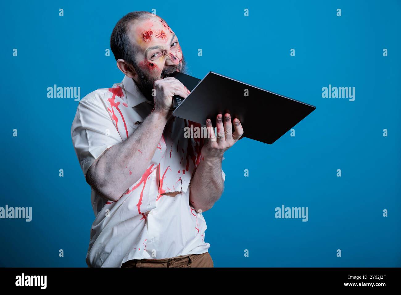 Raging man biting laptop in frustration, tired of capitalism rat race ...