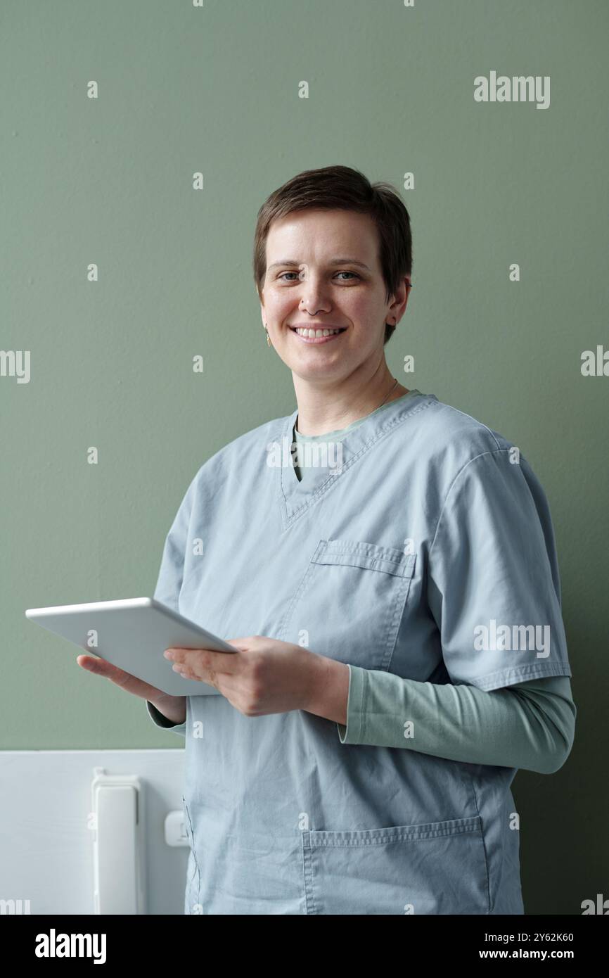 Portrait of smiling nurse holding digital tablet looking at camera in ...