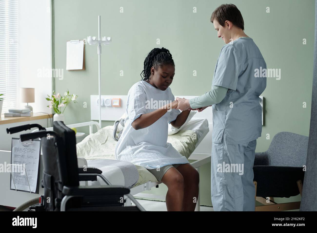 Medical professional assisting inpatient in hospital room while ...
