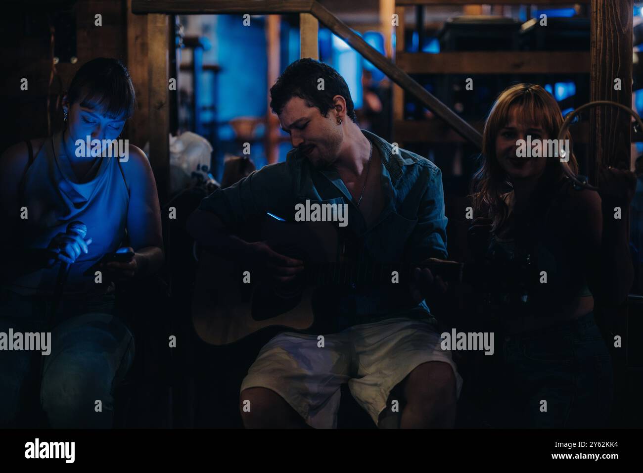 Young musicians performing in a cozy dimly lit venue, featuring a ...