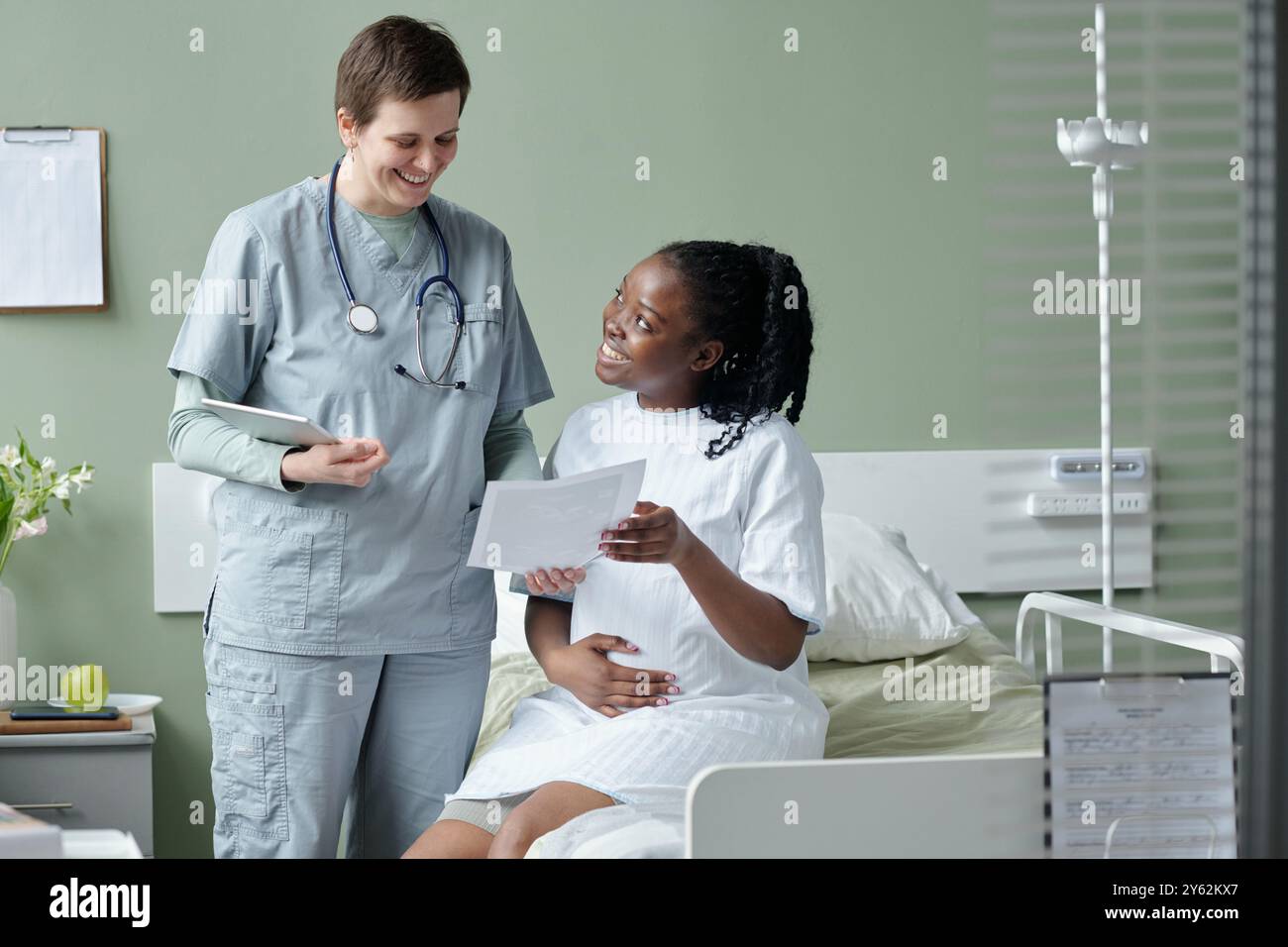 Doctor engaging with smiling child patient sitting on hospital bed ...