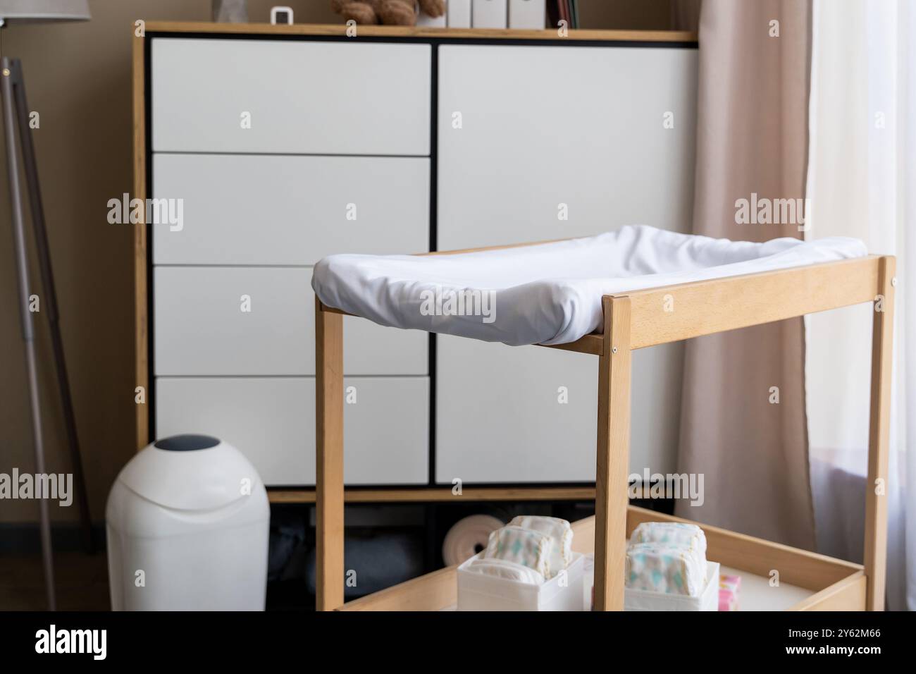 Empty nursery with changing table with diapers, lamp, commode and ...