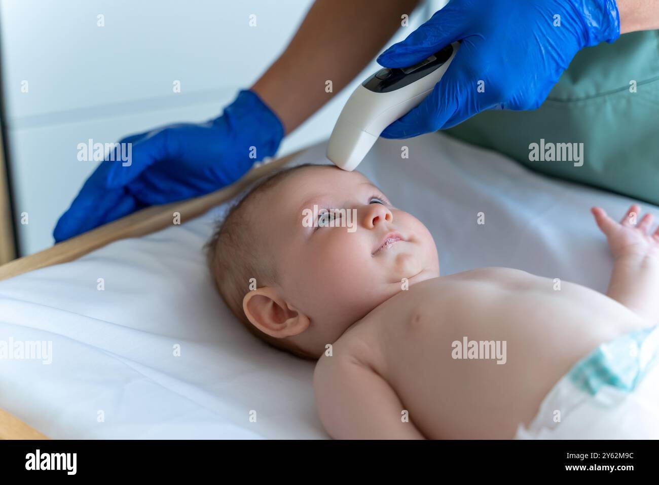 Doctor's hand holding thermometer at the child's forehead and measures ...