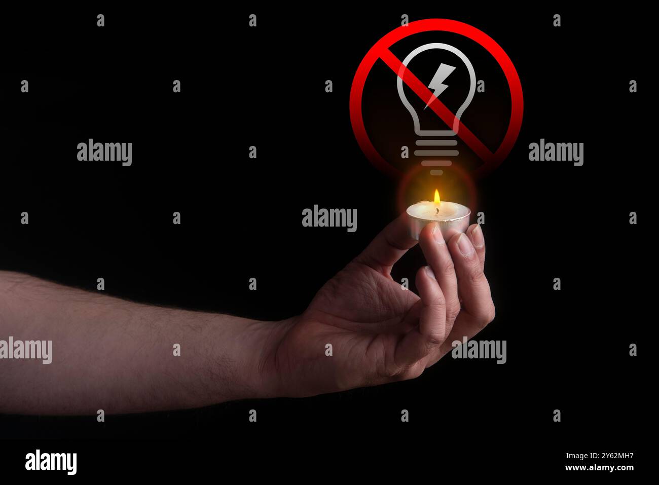 Man's hand holding a small white lit candle with a NO POWER icon on the ...
