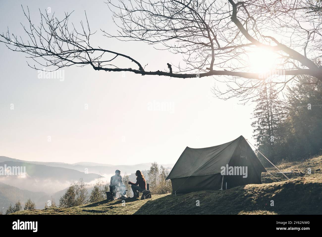 Sunny morning. Young couple having morning coffee while camping in ...